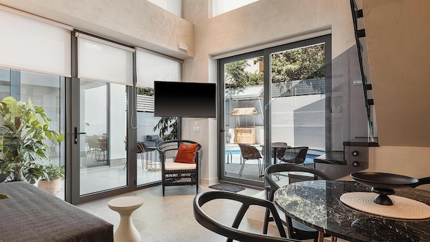 Interior moderno com área de jantar, televisão e vista para o exterior.