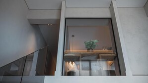 Um interior moderno com divisória de vidro, uma planta e uma prateleira de madeira.