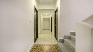 Um corredor moderno com piso de madeira, paredes brancas e escada à direita.