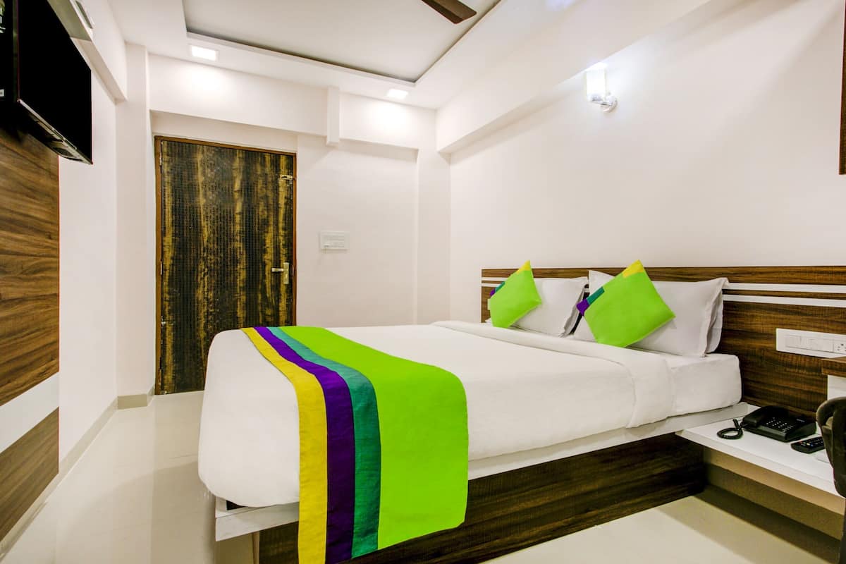 Quarto de hotel moderno com cama, mesa de cabeceira e escrivaninha com cadeira.