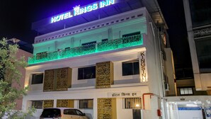 Um hotel com um letreiro de neon que diz "HOTEL KING'S INN" e uma varanda com iluminação verde.