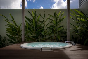 Uma banheira de hidromassagem com vista clara do céu e bambus ao redor.