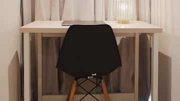 Uma mesa com um laptop, uma cadeira preta e um abajur branco.