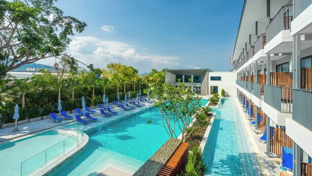 Um hotel moderno com piscina, espreguiçadeiras e vista para o mar.