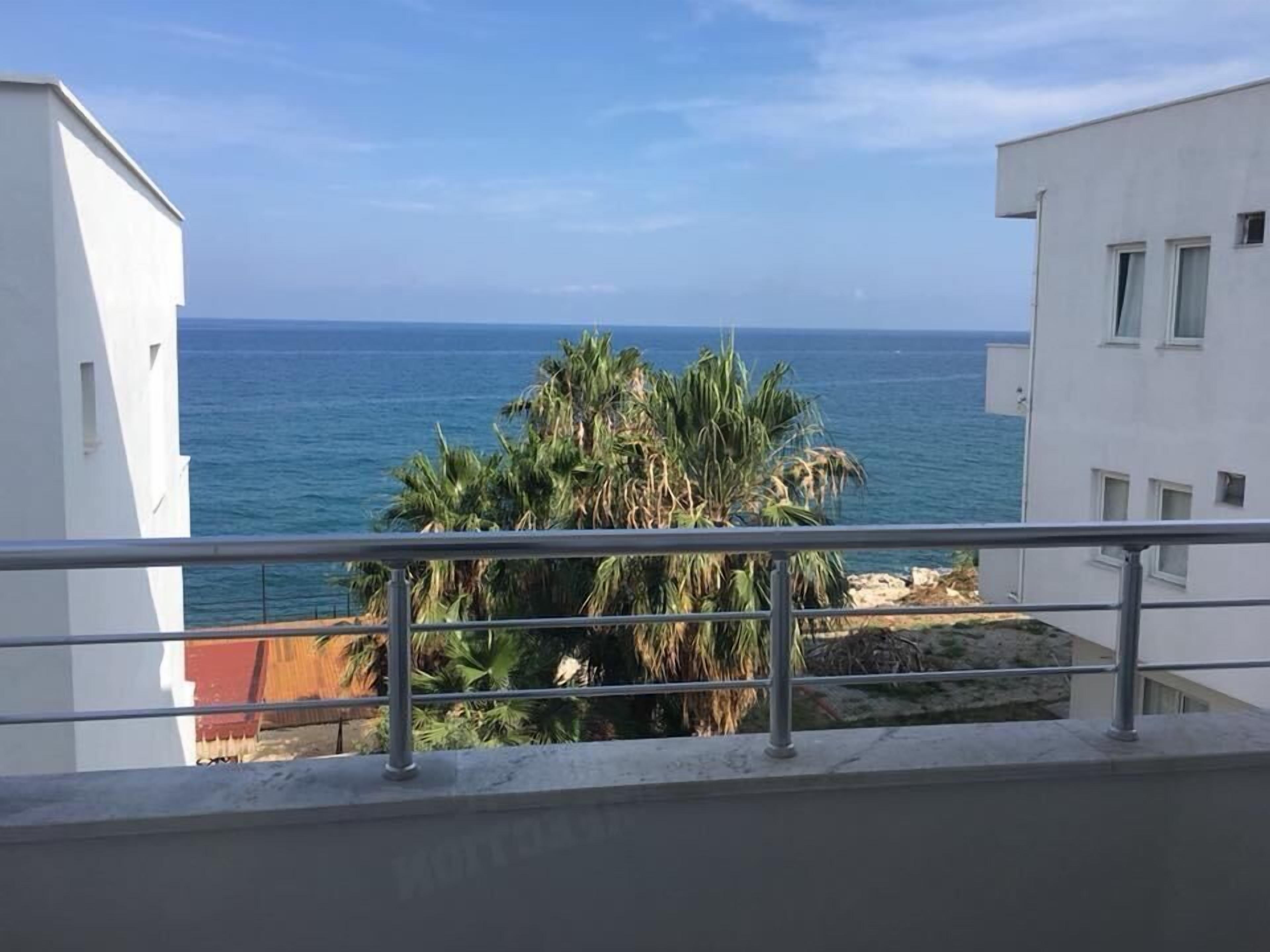 Uma varanda com vista para o mar e palmeiras.