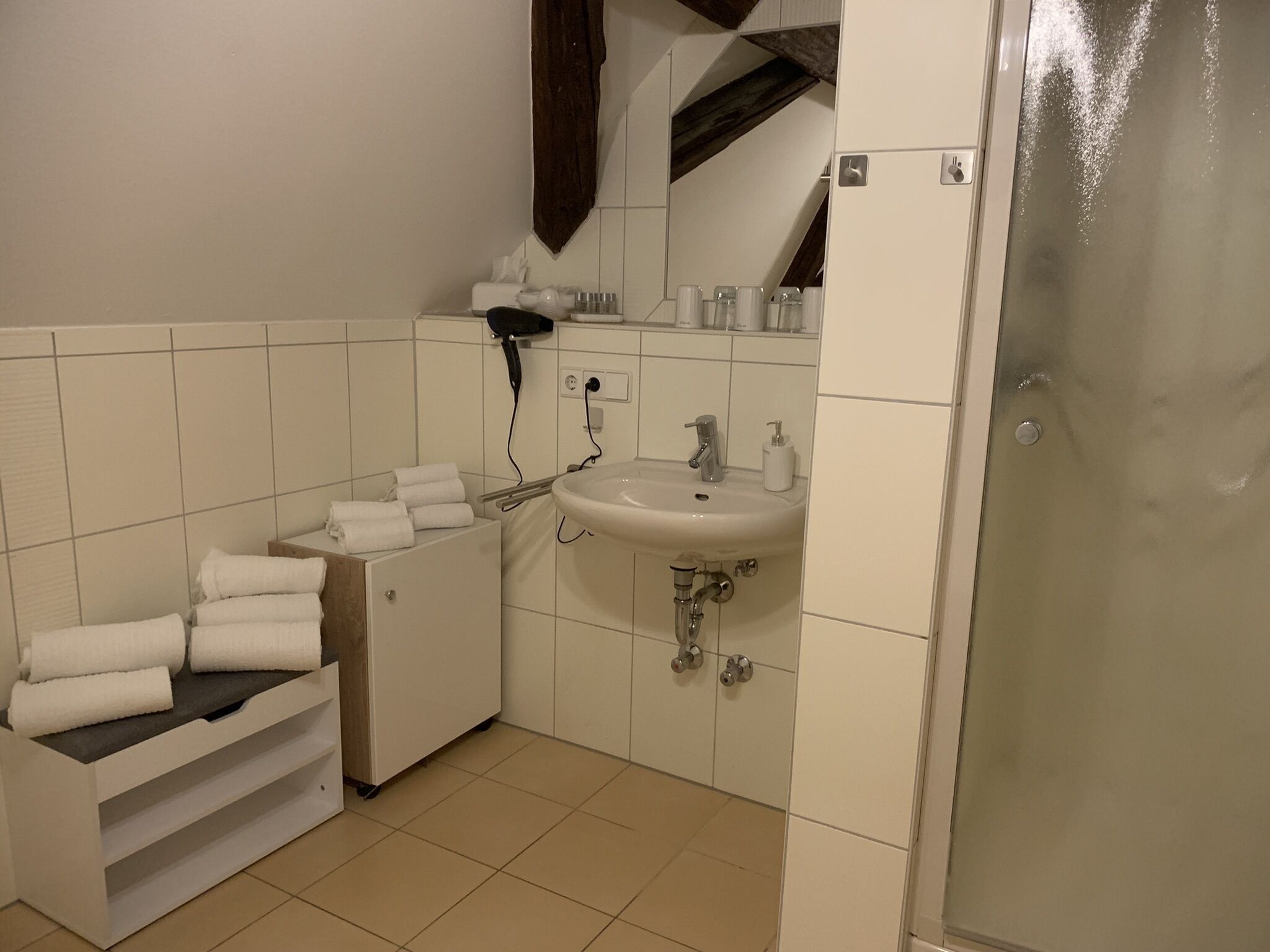 Casa de banho com lavatório, espelho, porta-toalhas e armário com toalhas.