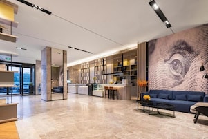 Um lobby moderno com balcão de recepção, área de estar e um grande mural abstrato.