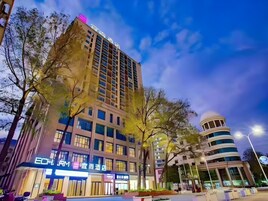Hotel com vários andares, fachada moderna, grandes janelas e um edifício de canto imponente com estrutura em cúpula.