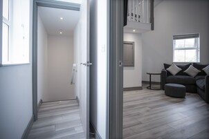 Uma sala de estar moderna com um sofá cinza, um banquinho e uma pequena mesa lateral.