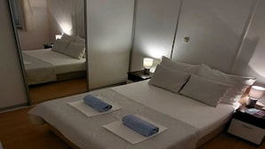 Quarto de hotel moderno com uma cama grande, uma mesa de cabeceira, um espelho e um ar condicionado fixado na parede.
