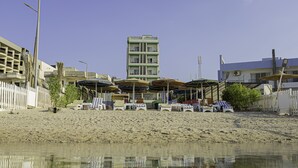 Um hotel à beira-mar com várias varandas, guarda-sóis e espreguiçadeiras.