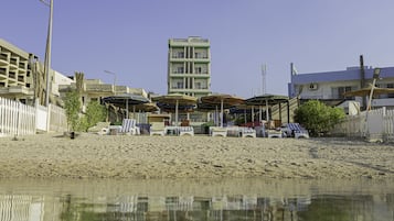 Praia particular, espreguiçadeiras, guarda-sóis, toalhas de praia