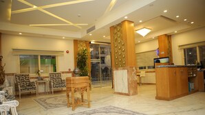 Um hall amplo com piso de mármore, mobiliário ornamentado e um grande tapete decorativo.