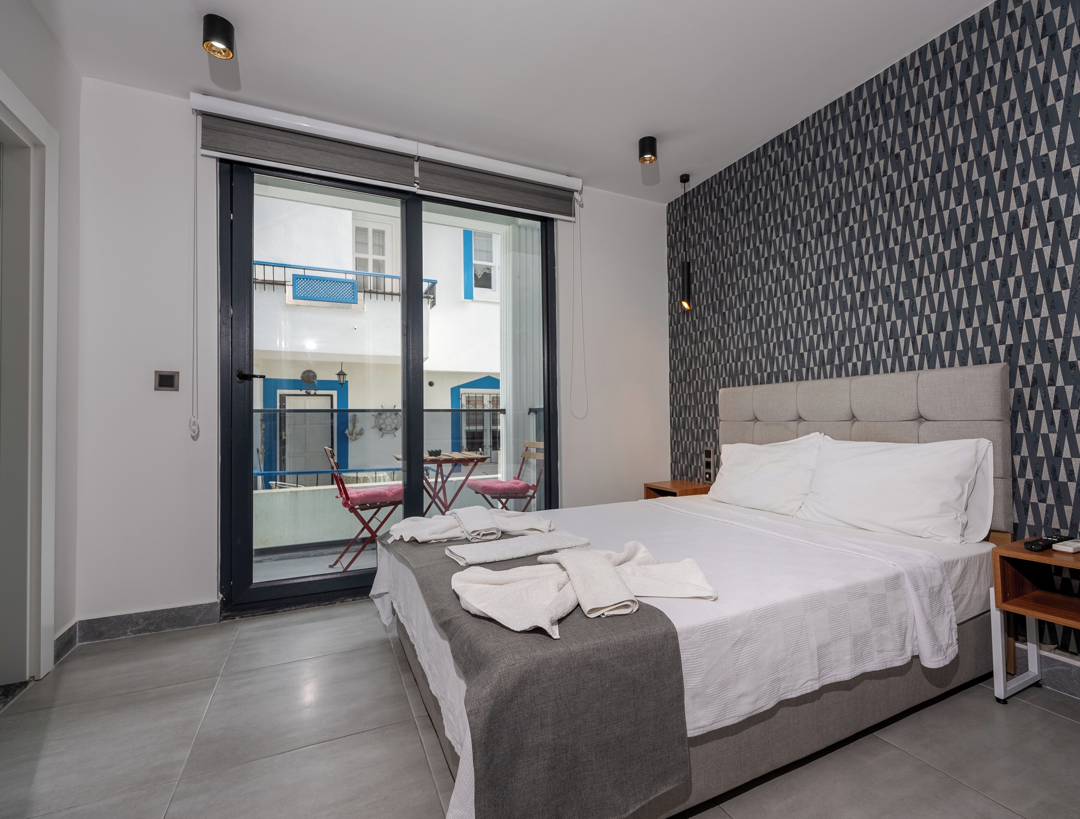 Quarto de hotel moderno com uma cama grande, uma varanda com vista e uma parede estampada.
