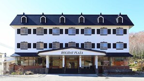 Um edifício com vários andares com uma placa na entrada que diz "HOLIDAY PLAZA".