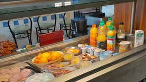 Buffet com diversos alimentos e bebidas, incluindo frutas, carnes e laticínios.