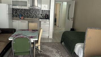 Quarto compacto com cozinha compacta, mesa de jantar e cama.