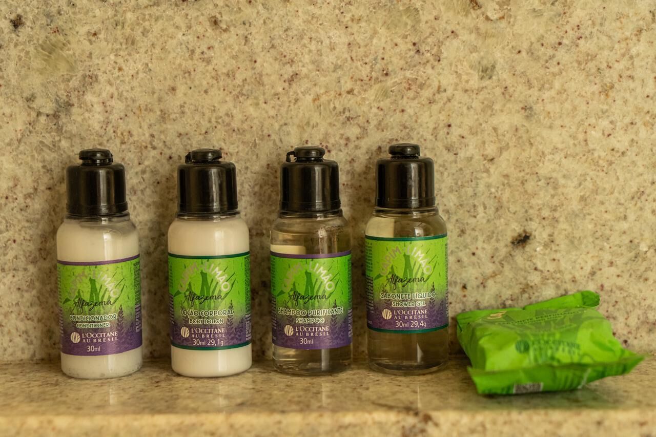 Três frascos de shampoo e um pacote verde em uma bancada.