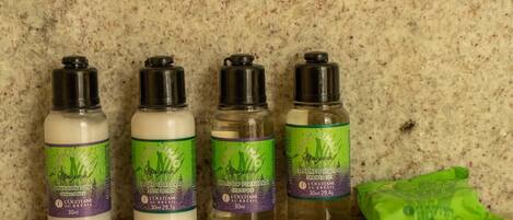 Três frascos de shampoo e um pacote verde em uma bancada.