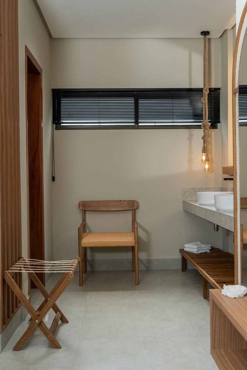 Um banheiro compacto com um banco de madeira, um porta-toalhas suspenso e uma prateleira pequena com produtos de higiene pessoal.