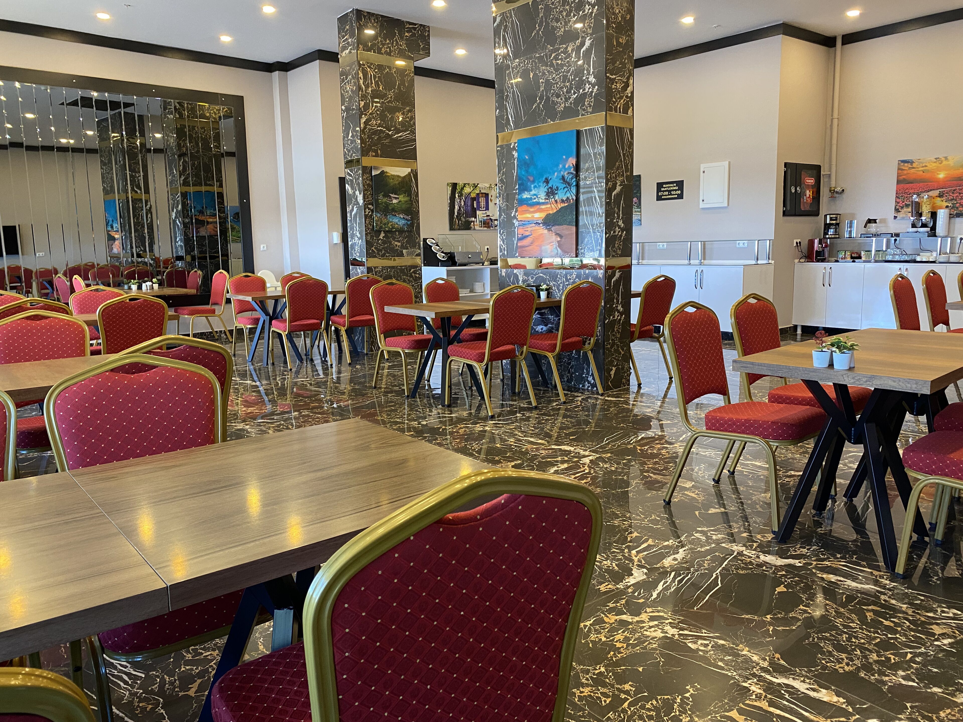 Restaurante com cadeiras vermelhas, piso de mármore e balcão com máquina de café.