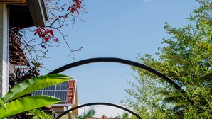 Uma passagem arborizada com um arco de metal que leva a um edifício com telhado em telhas.