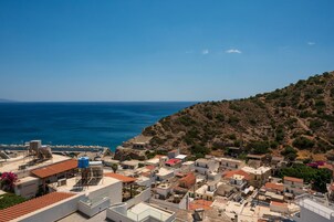 Uma vila costeira com edifícios, céu azul claro e o mar.