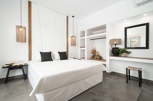 Quarto moderno com uma cama grande, luminárias pendentes, uma mesa de cabeceira com um livro e um pequeno banquinho.