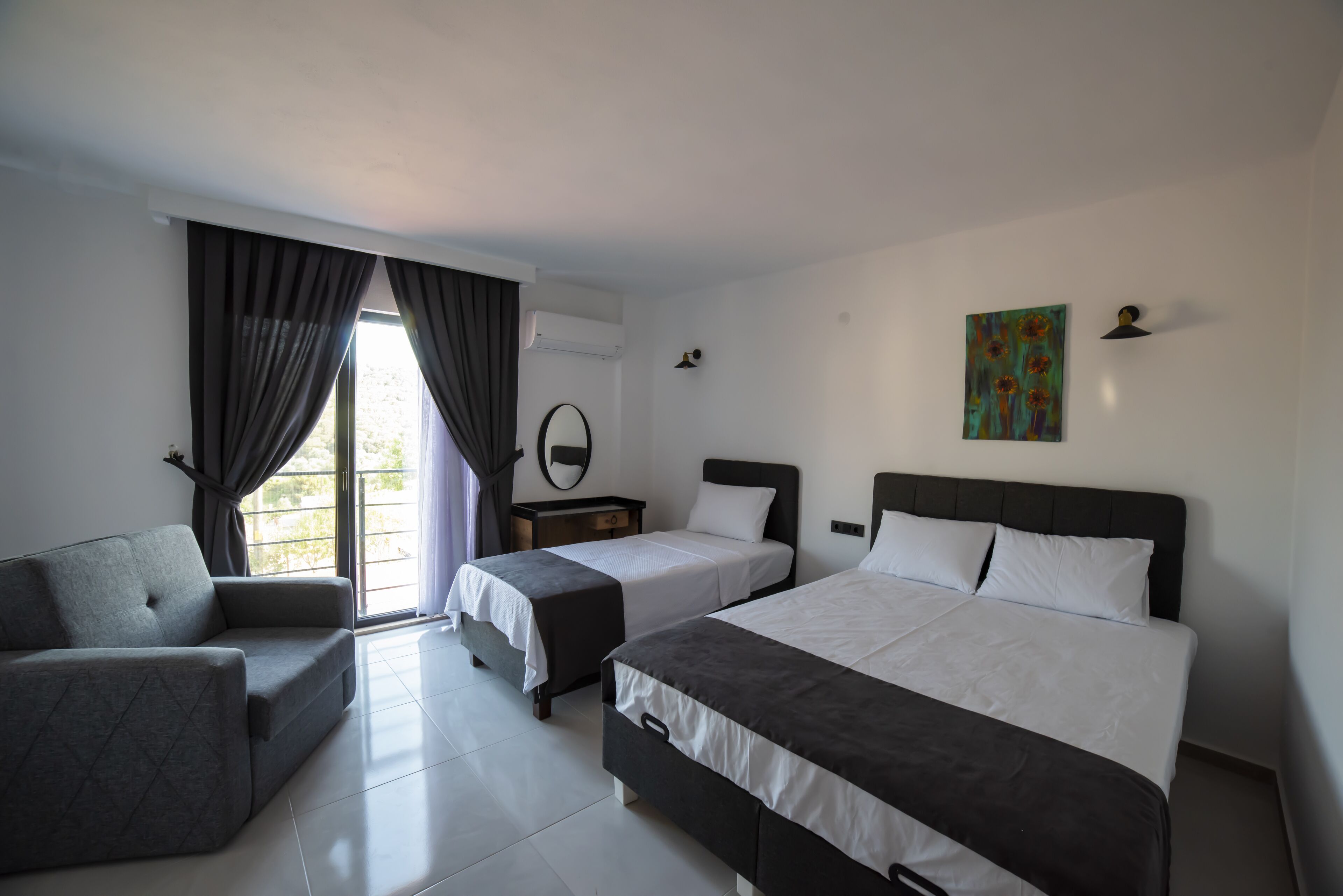 Quarto de hotel com duas camas, um sofá, uma mesa pequena e uma janela com cortinas.