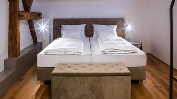 Quarto com uma cama grande, um banco e estrutura de vigas de madeira.