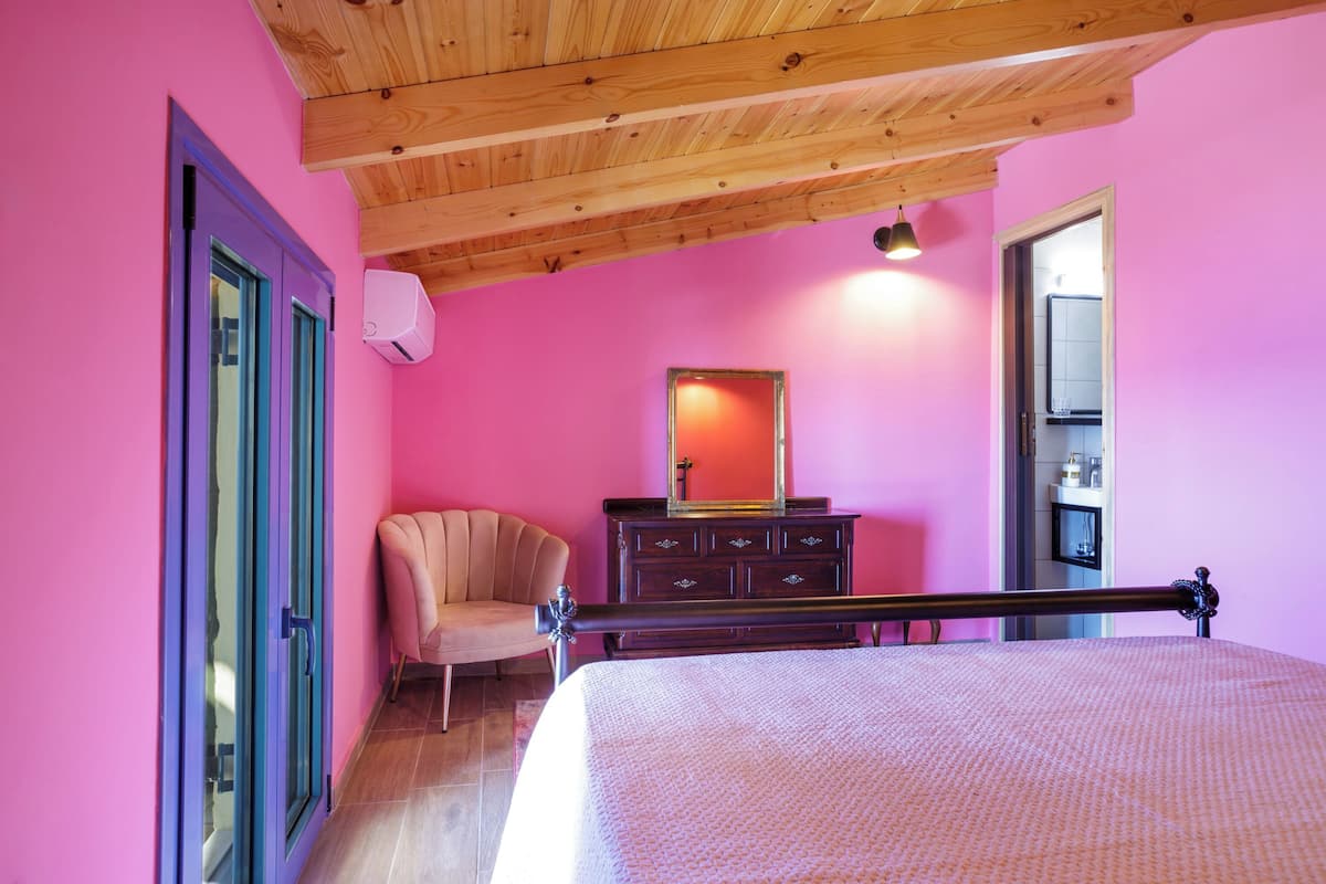 Quarto com cama, cadeira, cômoda e espelho.