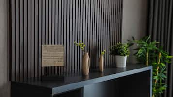 Um console moderno em tons escuros, com uma obra de arte de padrão geométrico, dois vasos com flores amarelas e uma planta em vaso.