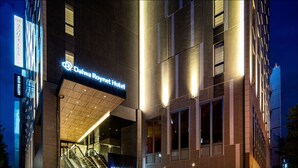 Entrada do Hotel Daiwa Roynet, com fachada de vidro, uma escadaria e uma placa sobre a entrada.