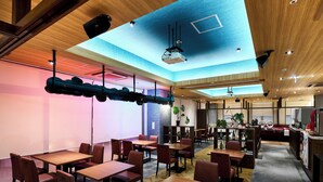 Um restaurante moderno com mesas e cadeiras de madeira, teto com iluminação azul e área de bar.