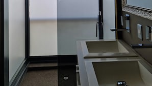 Casa de banho moderna com uma janela ampla que oferece vista para um corpo de água e montanhas ao longe.