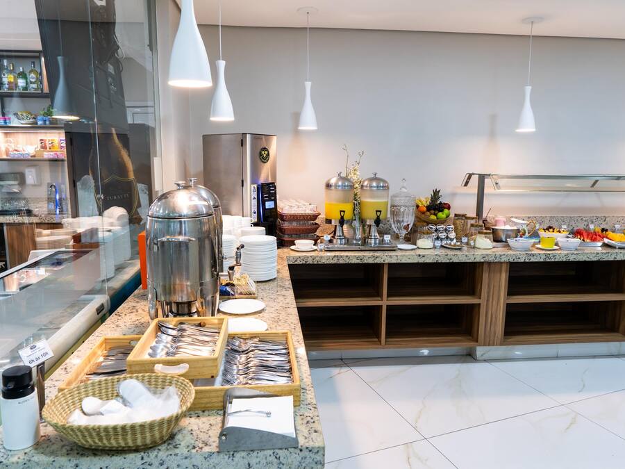 Disposição de buffet com diversos alimentos, acompanhamentos e utensílios de servir.
