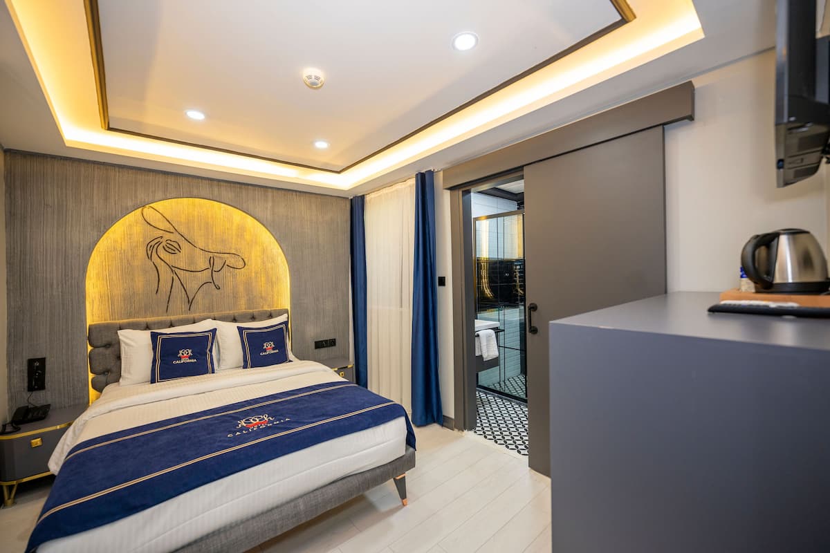 Quarto de hotel moderno com uma cama grande, uma escrivaninha e zona de chuveiro.