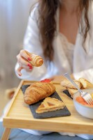 Uma bandeja com doces, incluindo um croissant, uma fatia de torta e uma pequena tigela de frutas.