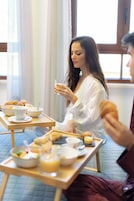 Uma mesa de café da manhã com uma bandeja de croissants, tigelas de frutas e um copo de suco de laranja.