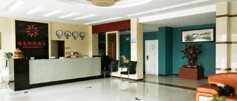 Área de recepção de hotel com balcão, cadeiras, um candelabro e um balcão de atendimento.