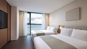 Quarto de hotel com duas camas, uma janela ampla com cortinas, uma televisão de tela plana e uma obra de arte abstrata na parede.