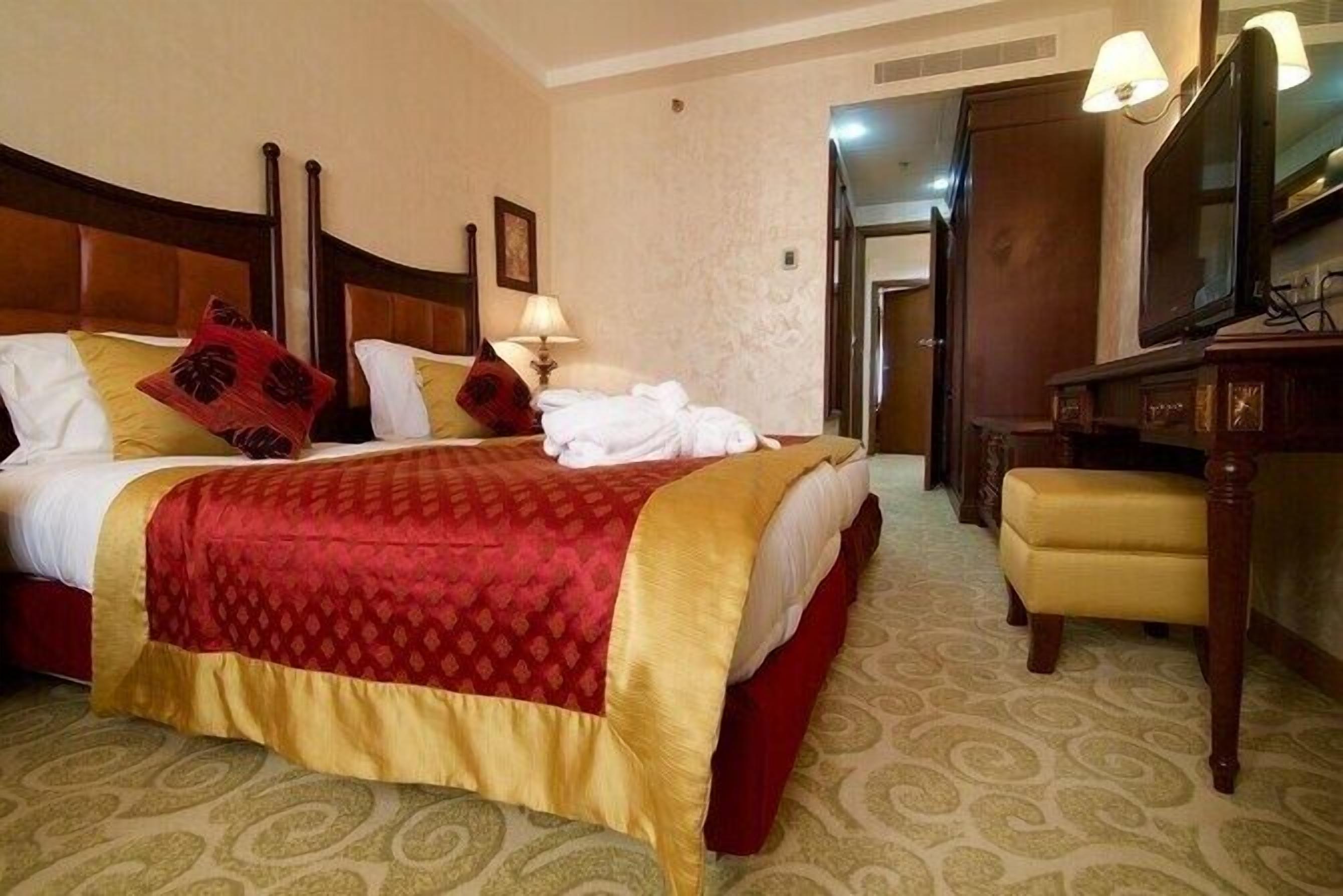 Quarto de hotel com uma cama grande, uma escrivaninha, uma televisão e uma cadeira.