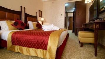Quarto de hotel com uma cama grande, uma escrivaninha, uma televisão e uma cadeira.