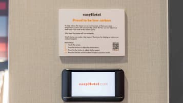 Uma placa com texto e um código QR, e um smartphone exibindo o site easyHotel.com.