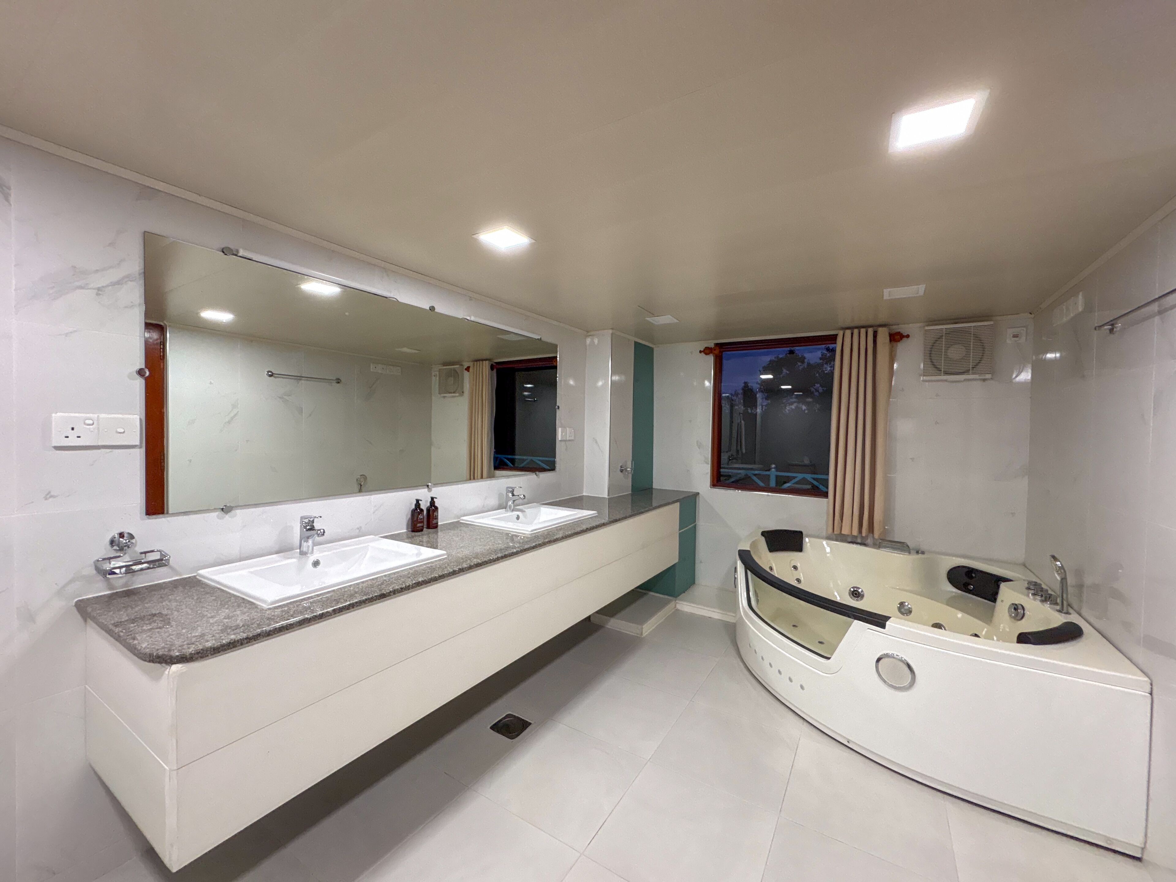 Uma casa de banho moderna com duas pias, um espelho grande, uma banheira e uma janela com cortinas.