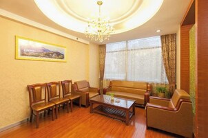 Quarto com sofá, cadeiras, mesa de centro e lustre.