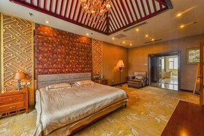 Quarto com cama grande, cabeceira de madeira, lustre e papel de parede estampado.