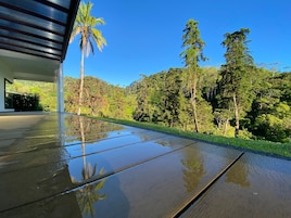Um terraço moderno ao ar livre com vista desobstruída para uma floresta exuberante e árvores altas.