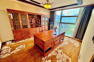 Quarto espaçoso com uma grande escrivaninha de madeira, estantes embutidas e uma ampla janela com vista para a cidade.
