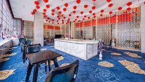 Um hall de hotel com balcão de recepção, área de estar e elementos decorativos.